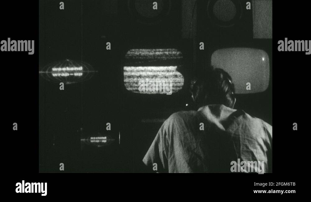 1950s: View from behind, man in TV control room, zoom in on monitors ...