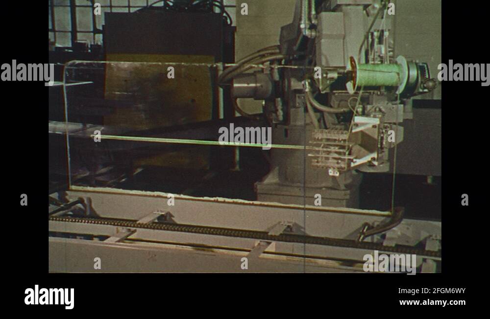 1980s: industrial robotic arm in factory strings wire through fixture ...