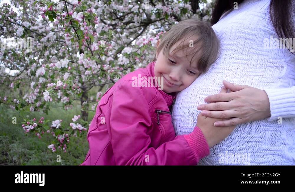 Pregnant mother hugging daughter in blossomed spring Park. Daughter ...