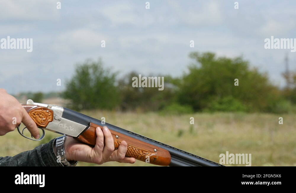Some man aiming and shooting from a double barrel rifle in field in ...