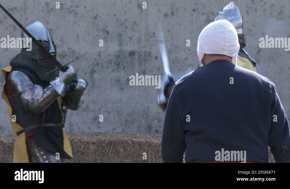 Medieval combat. Two men dressing antique metal armor fight a sword ...