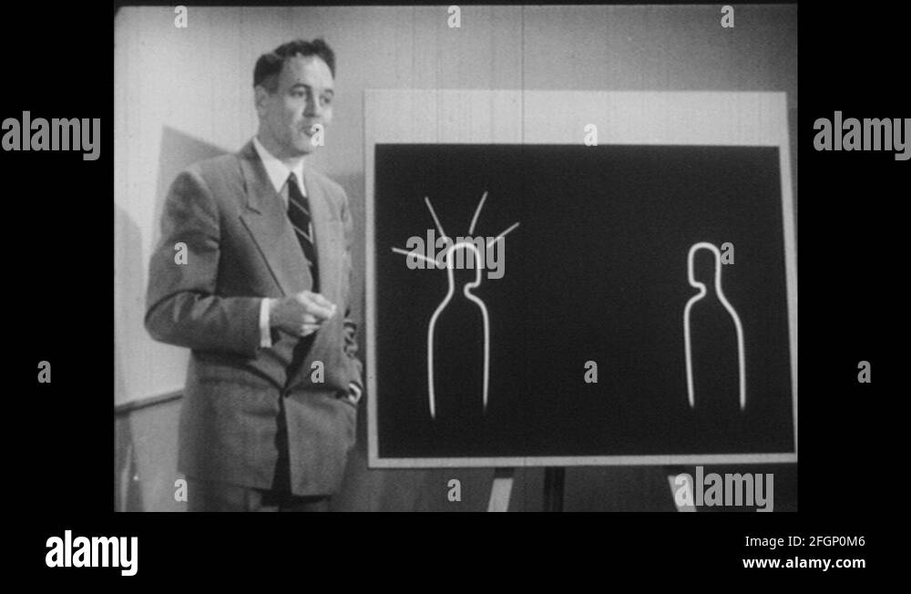 1950s: Male professor stands at chalkboard with drawing of two people ...