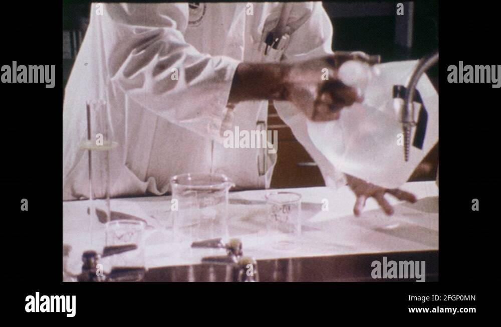 1970s: Lab technician shakes plastic container of water sample. He ...