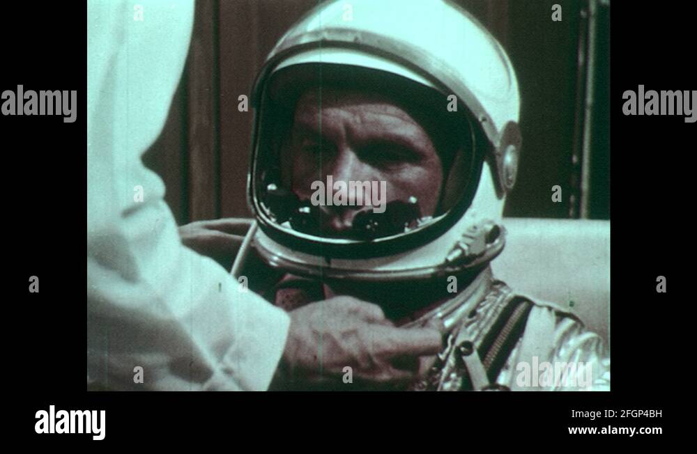 1960s: Man in white lab coat attaches helmet to astronaut John Glenn in ...