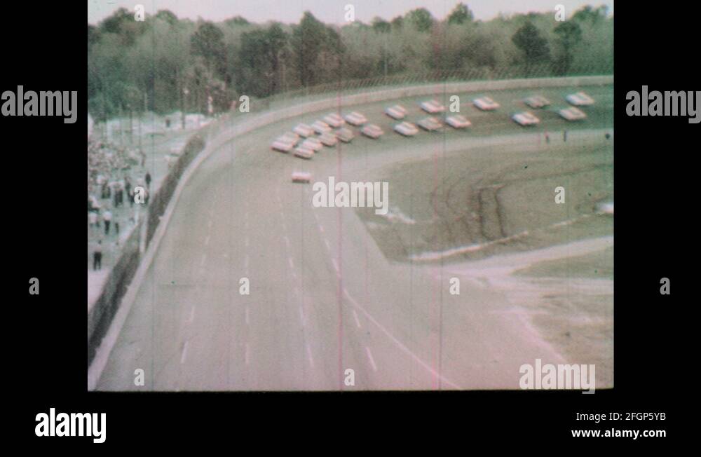 1960s: Pace car pulls off race track. Cars begin race. Cars speed down ...