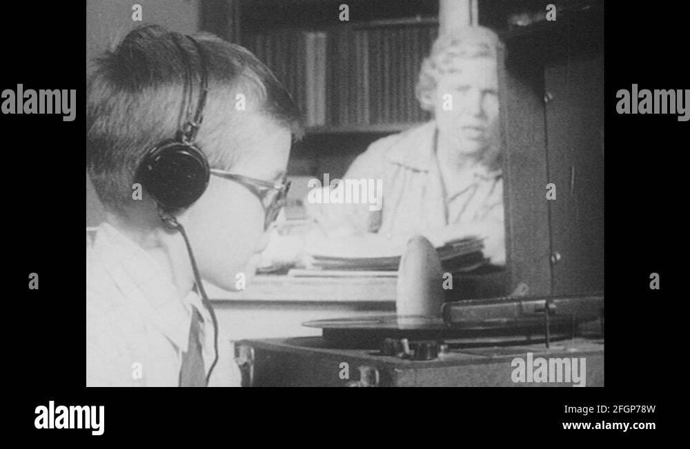 1950s: Boy listens to recording on phonograph. Boy speaks with teacher ...
