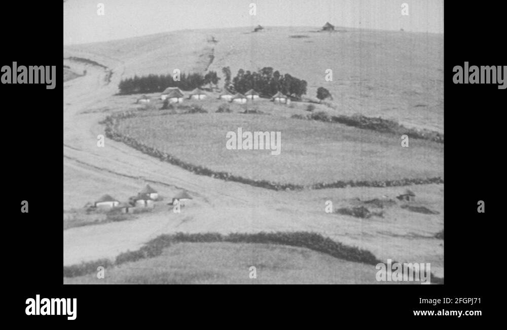 South Africa 1960s: Cluster of huts on land. People walk to fence Stock ...