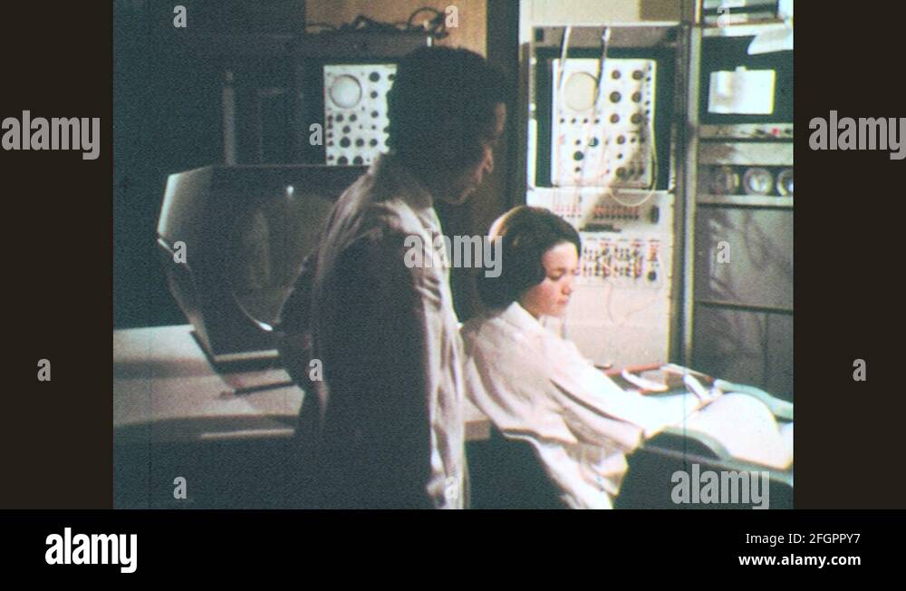 1970s: Woman and man in lab. Man leaves. Man looks in microscope ...