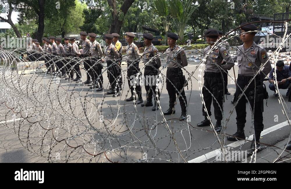 Uniformed police officers behind barbed wire security blockade Jakarta ...