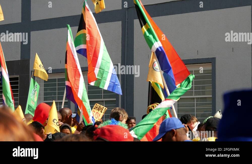 South African flags with small yellow flags above heads of group of ...