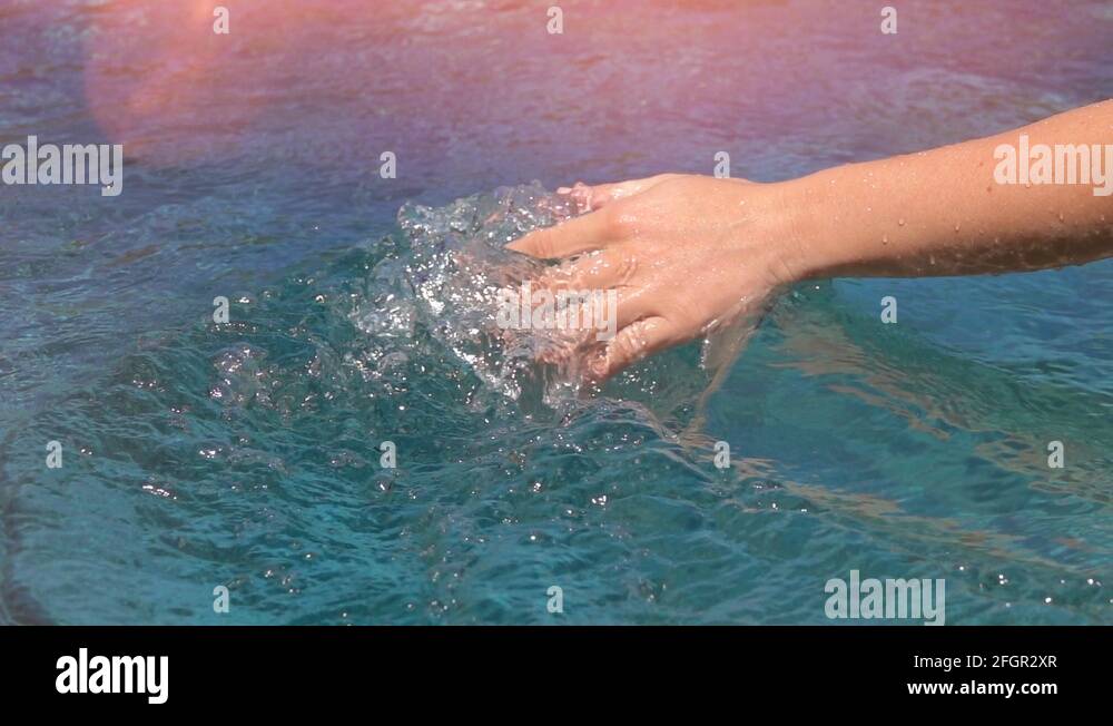 SLOW MOTION, LENS FLARE: Detail of woman dragging her hand through ...