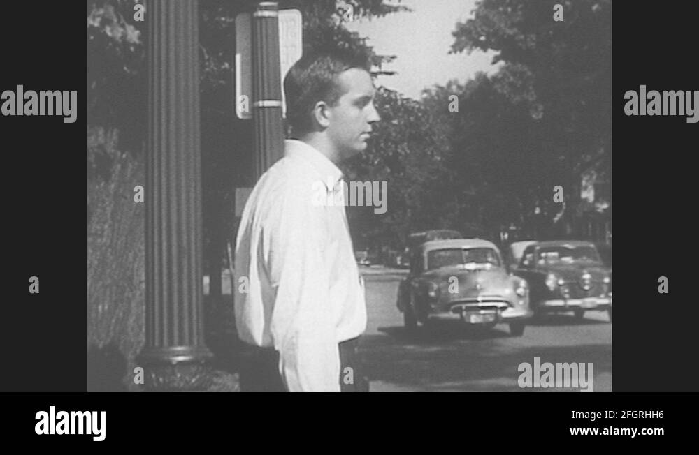 1950s: Boy at street corner. View of traffic light. Boy crosses street ...