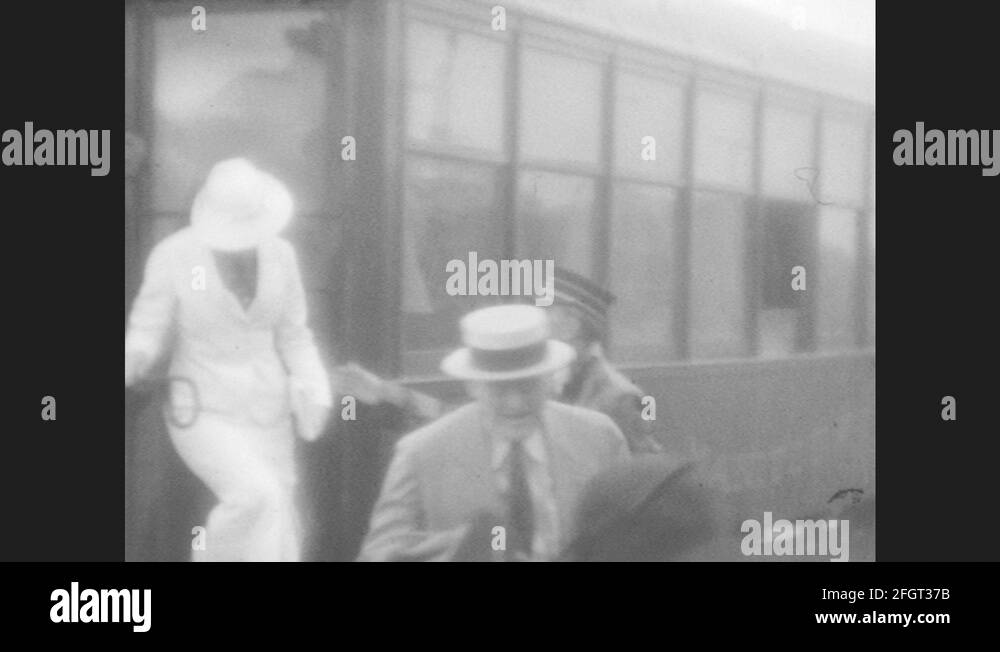 1930s: people climb down steps of train onto ground. Rain and snow in ...