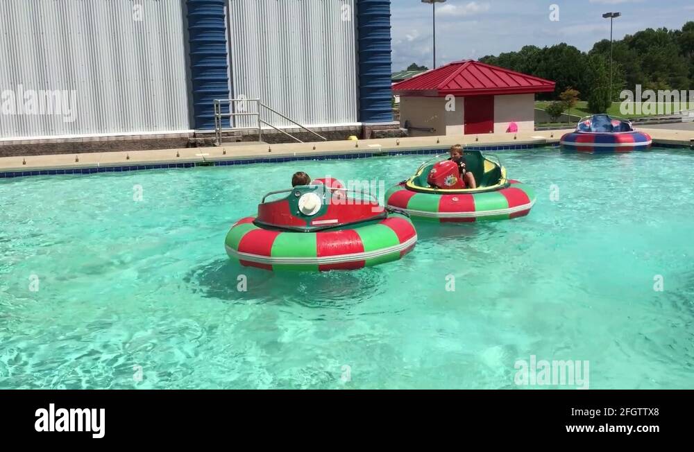 Two boys playing in water bumper boats at amusement park on summer ...
