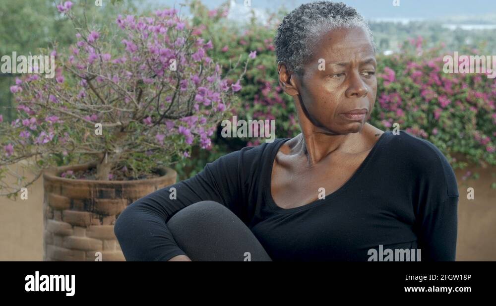 African American baby boomer woman moving into yoga half spinal twist ...