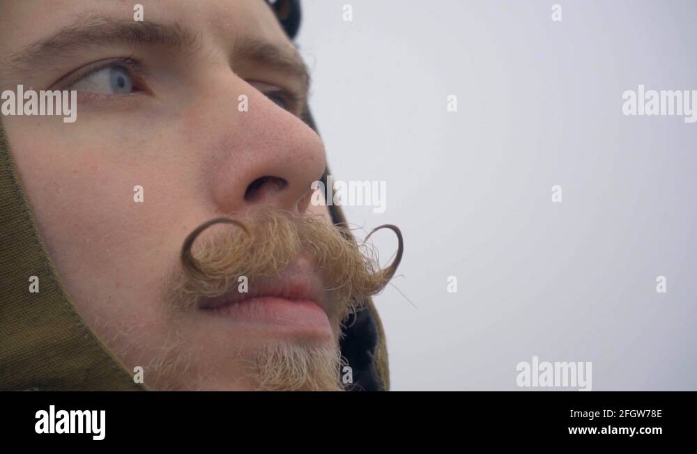 A light-eyed male pilot in the style of the 60's stands with a twisted ...