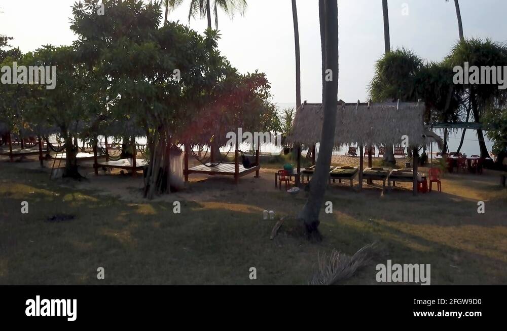 Rising aerial camera from the ground with day beds and palapas to above ...