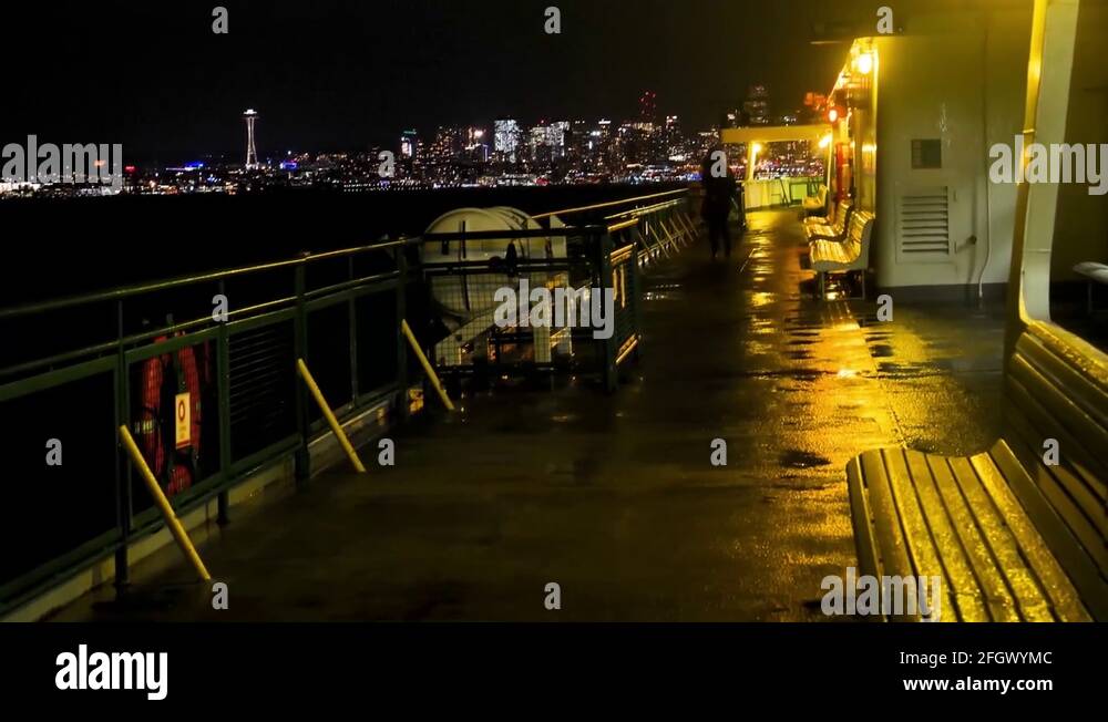 Night Passengers stroll wet lighted ferry deck Seattle lights Rolling ...