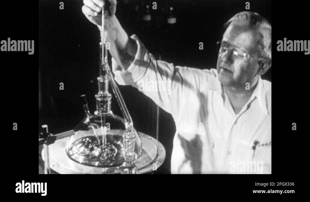 1940s: Male scientists stand in laboratory. Beakers and flasks bubble ...