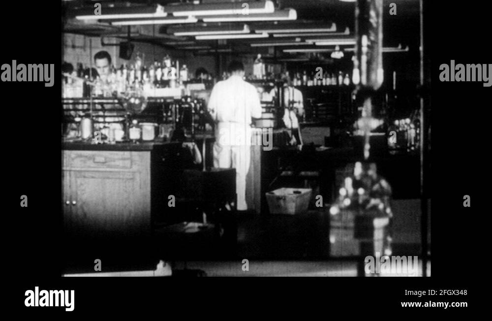 1940s: Male scientists stand in laboratory. Beakers and flasks bubble ...