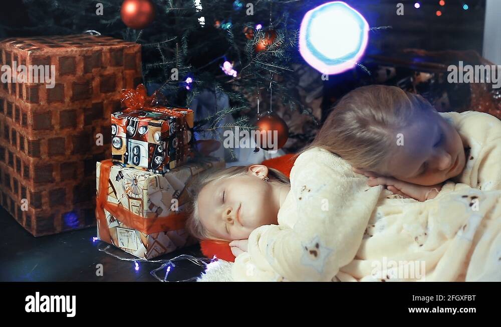 two girls asleep under the Christmas tree Stock Video Footage - Alamy