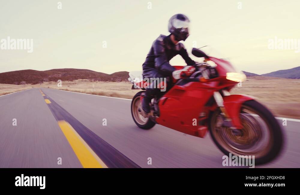 Motorcyclist racing his motorcycle down straight country road going a ...