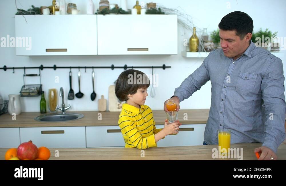 Father pouring orange juice for very cute boy. slow motion. Father's ...