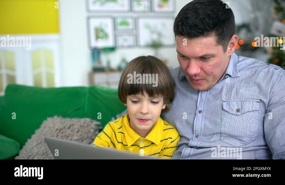 Father and son using laptop. Handsome father looking at computer with ...