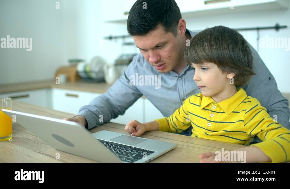 Father and son using laptop. Handsome father looking at computer with ...