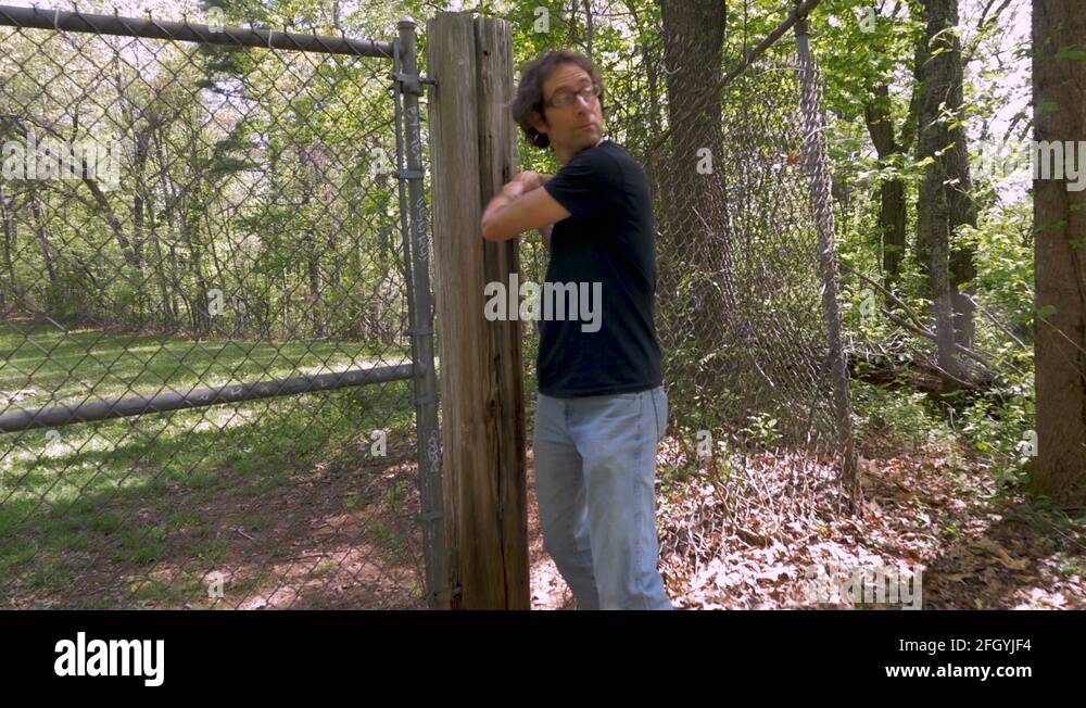 Wide of a man breaking into a chained off area and creeping into the ...