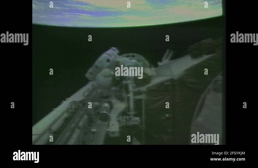 1980s: Astronauts work on outside of space shuttle. Man holds on to ...