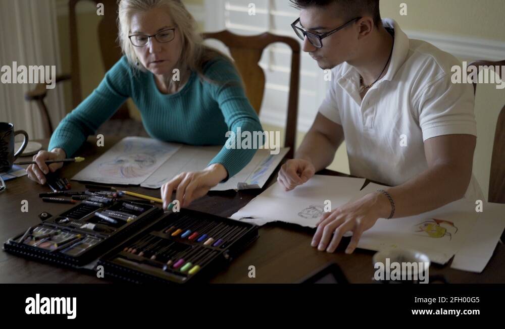 Focus shift from young teen man and his mother working on pencil ...