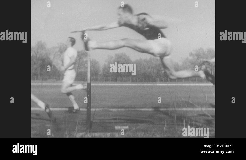 1950s: Slow motion side view of men running behind hurdle and man ...