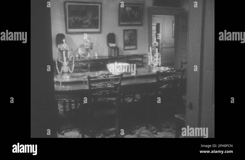 1950s: Colonial dining room. Candelabras and silver service on dining ...