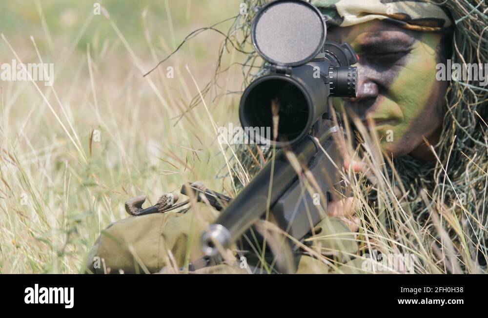 Army sniper lying and aiming in grass carrying his gun Stock Video ...