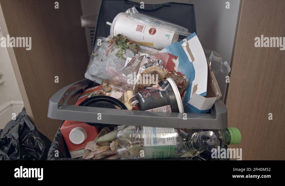 Throwing rubbish into a kitchen bin with recyclable and non recyclable ...