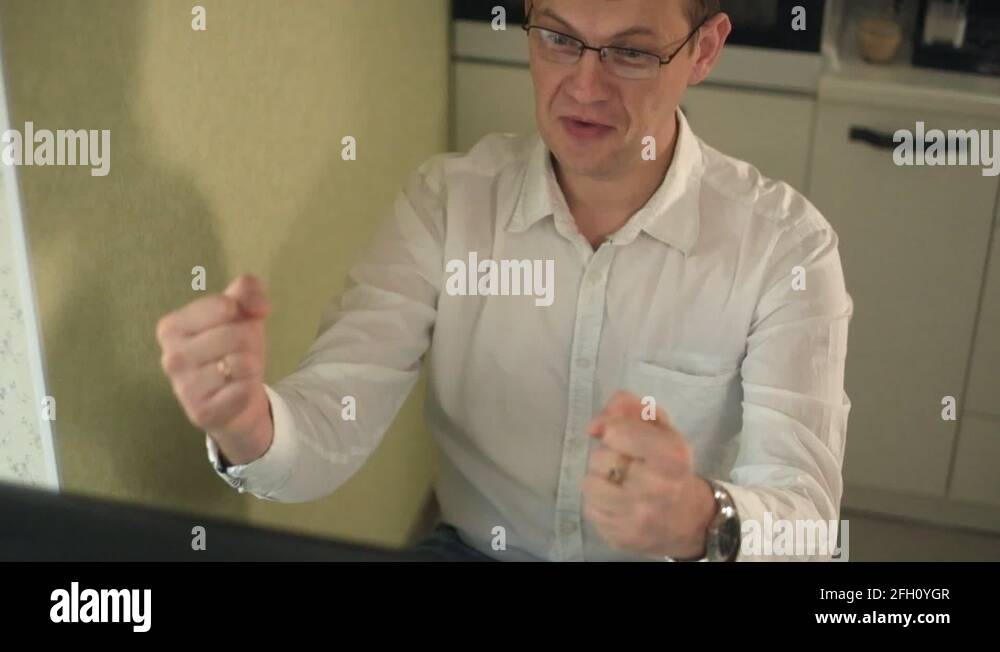 Excited screaming young man looking at the screen of his computer and ...