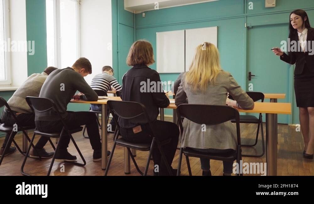 Woman teacher check students progress during a lesson in classroom ...