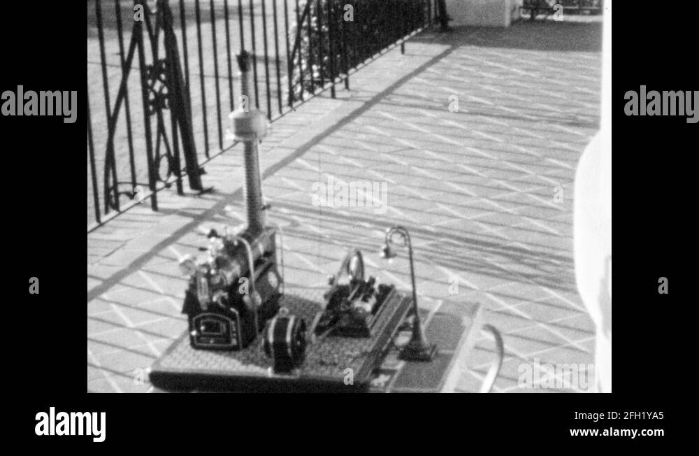 1930s: Model engine sits on small table. Boy demonstrates model engine ...