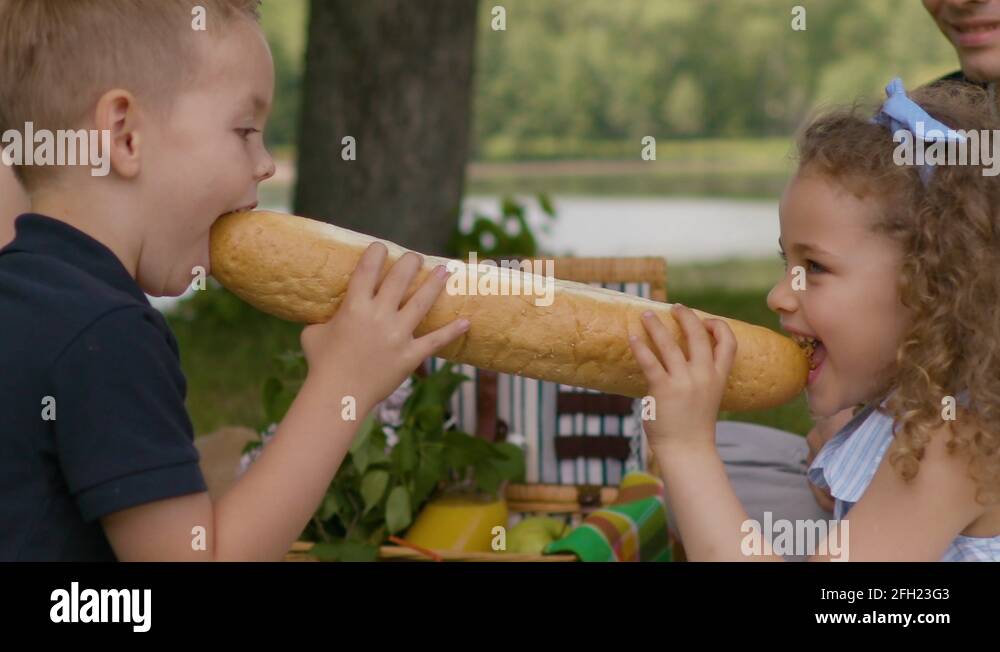 Children compete who will bite off a bit of a loaf at a picnic in slow ...