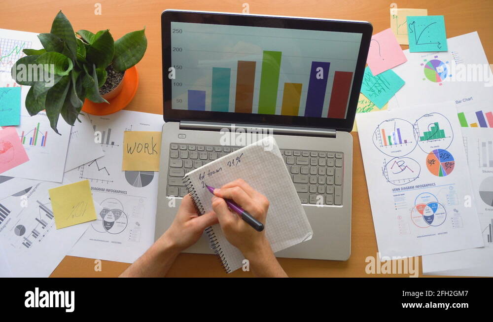Man writing in notepad at office surrounded by a lot of paperwork, top ...