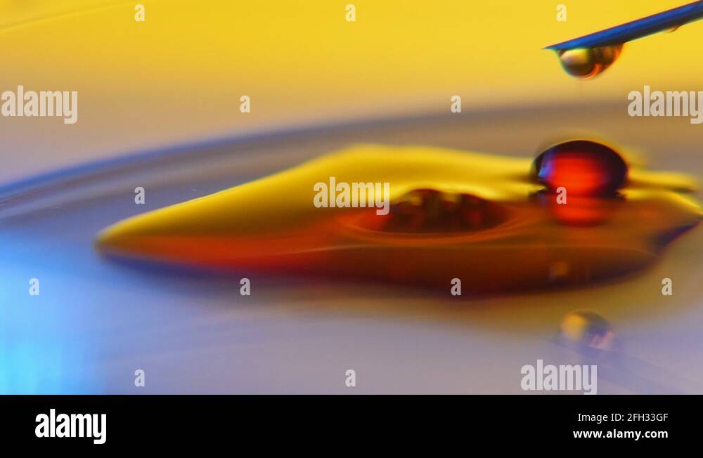 Red blood blobs fall from needle on liquid surface looking like a tiny ...