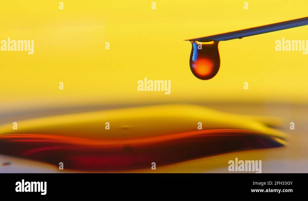 Red blood drops fall from needle on fluid surface looking like a small ...