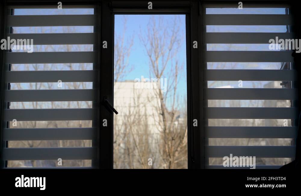 man is approaching to windows inside a home against light and dropping ...