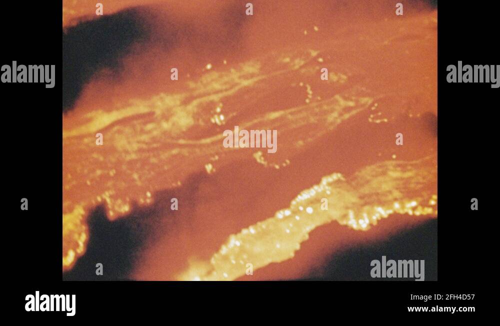 1950s: Bright red lava flow with islands of rock/earth. Man operates ...