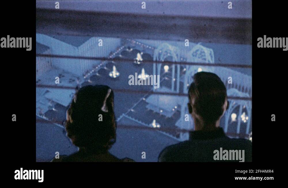 1960s: Rear view, boy and girl look at fairgrounds, walk off screen ...