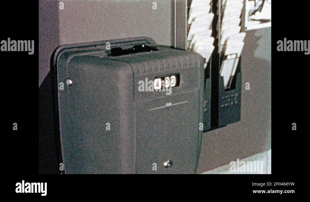 1950s: Punch clock. Men approach punch clock. Hand pushes card into ...