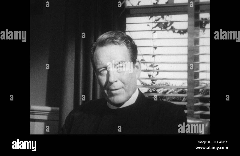 1960s: Priest seated in front of window talks. Young man sits and ...