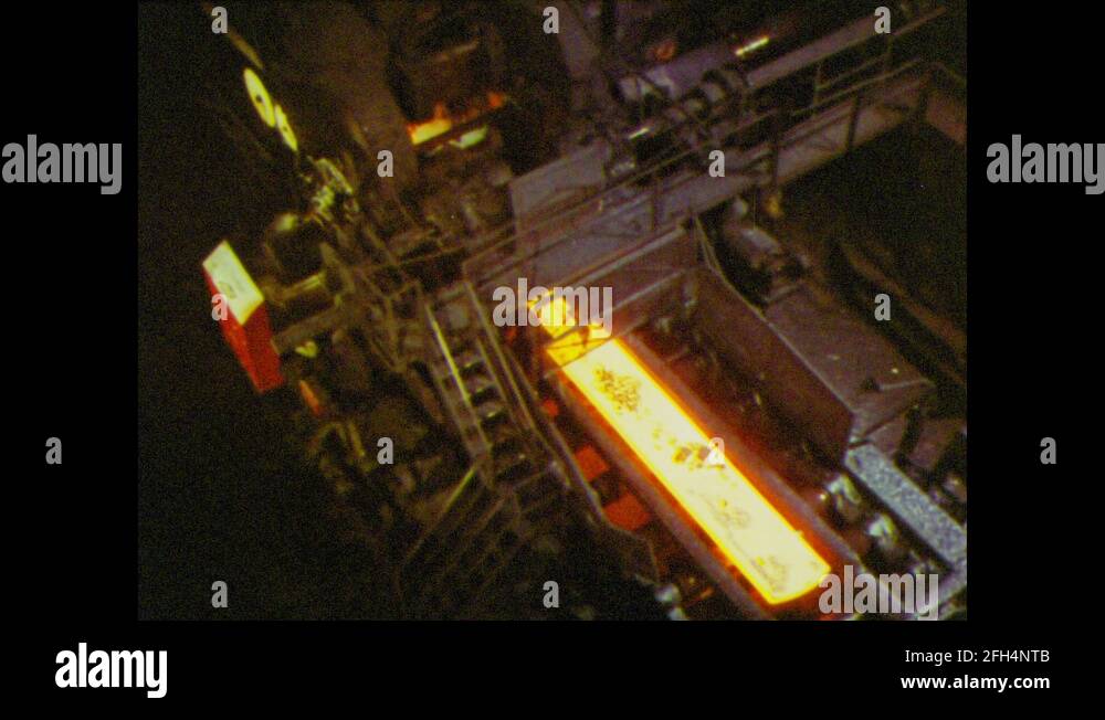 1960s: UNITED STATES: steel slab in roughing process. Steel on conveyor ...