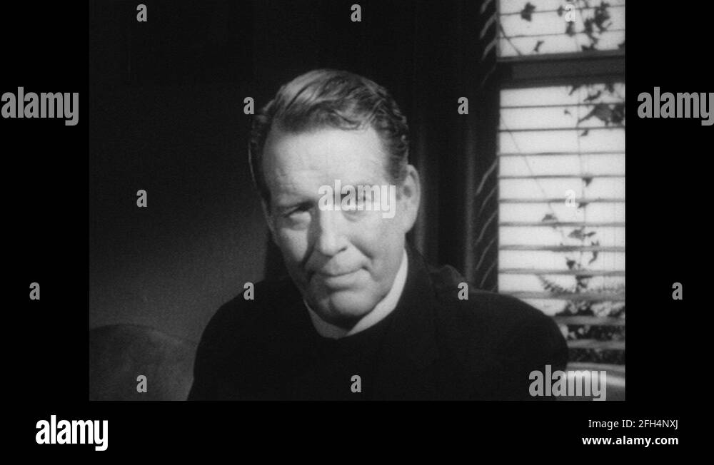1960s: Priest seated in front of window talks. Young man sits and ...